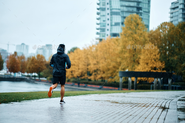Back view of male athlete running outdoors in the rain. Stock Photo by ...
