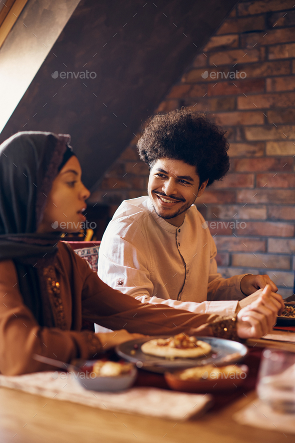 Young happy Muslim man enjoying in conversation with his wife during ...