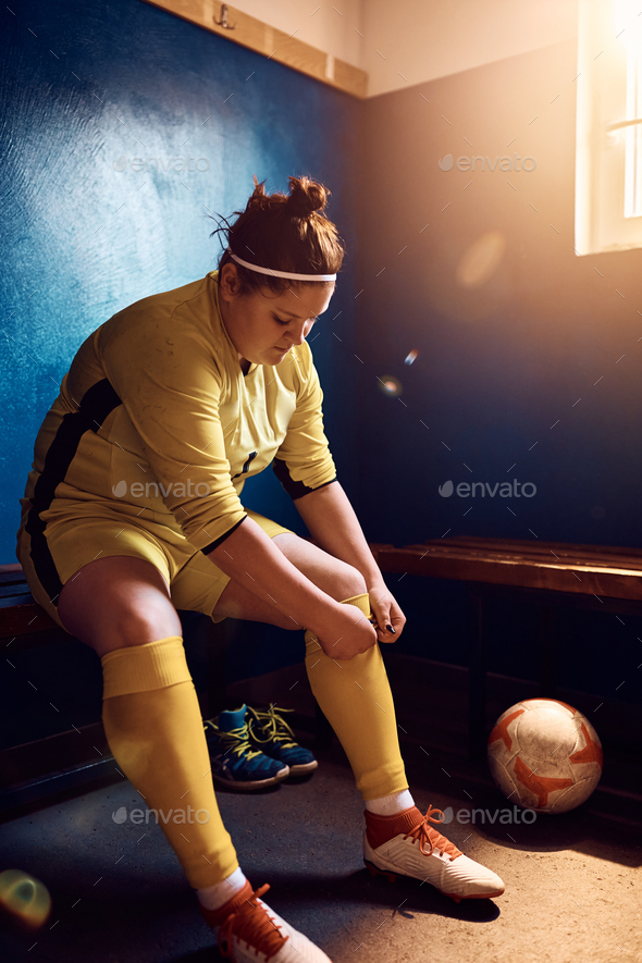 Female goalkeeper getting dressed in locker room before the match ...
