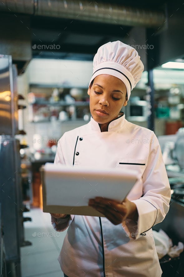 African American female chef taking notes while working in a restaurant ...