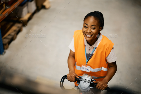 Above view of happy black female worker using pallet jack at ...