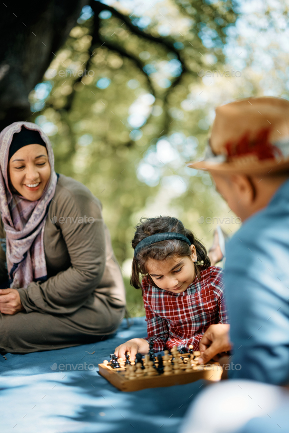 Small Muslim girl playing chess while spending spring day with her ...