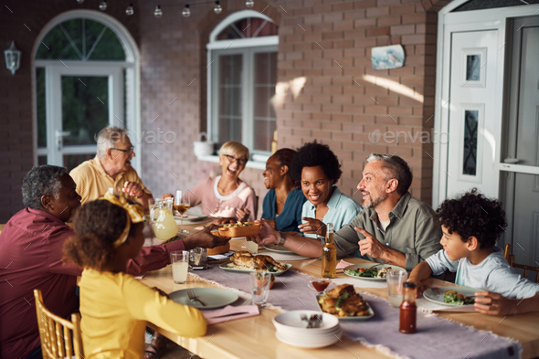 Happy multiethnic extended family eating at dining table on a patio ...