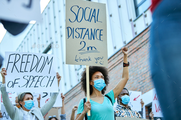 Below view of crowd of people with face masks protesting during COVID ...