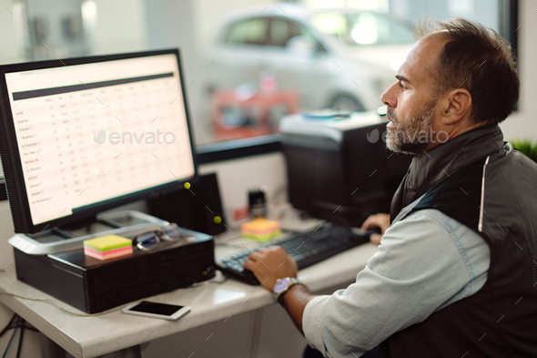 Male foreman working on desktop PC in auto repair office. Stock Photo ...