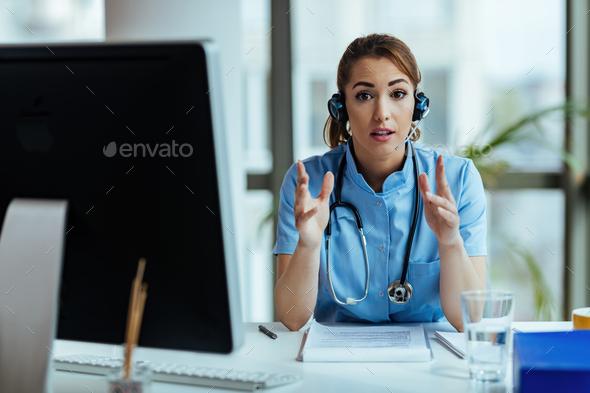 Young nurse with headset providing support while working at medical ...