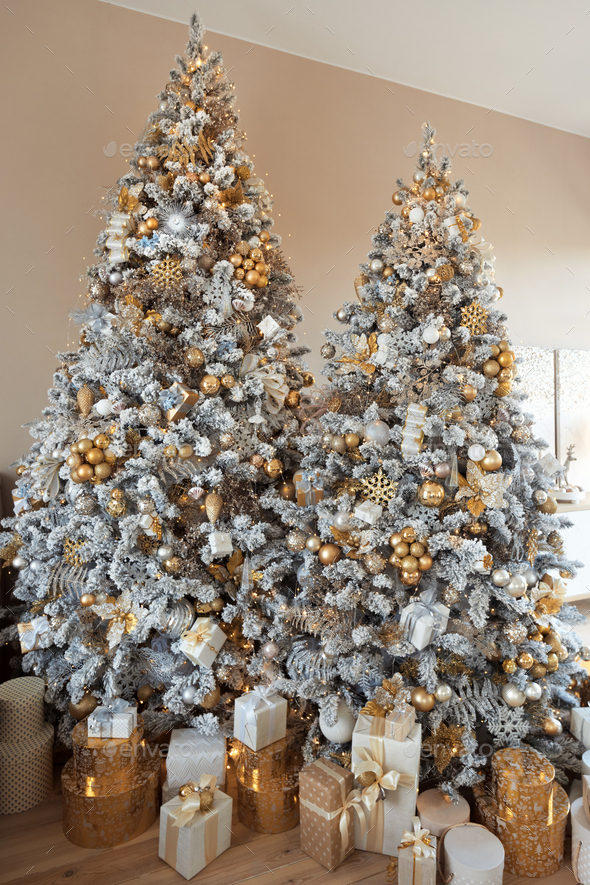 Vertical photo of two huge rich christmas tree with many presents in ...