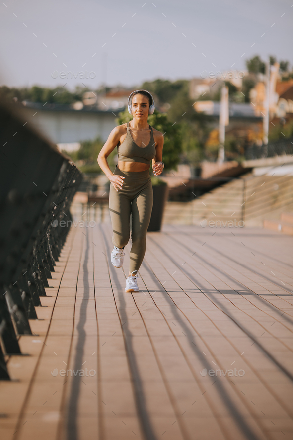 Active young beautiful woman running on the promenade along the ...