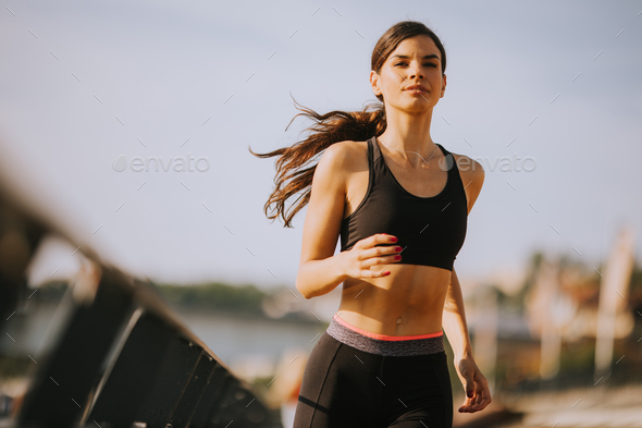 Active young beautiful woman running on the promenade along the ...