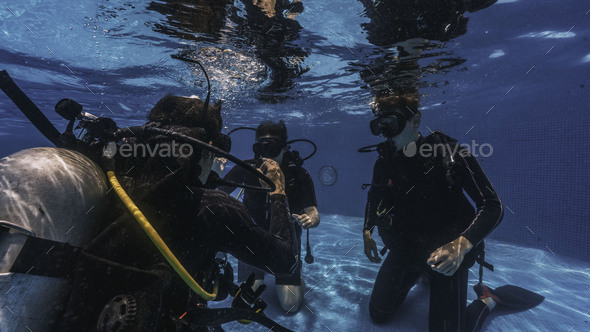 diving instructor teaches students to scuba dive in swimming pool ...