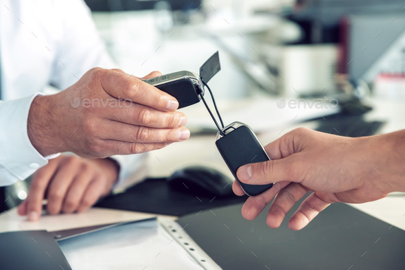 Car salesman gives the keys to the customers who signed the purchase ...