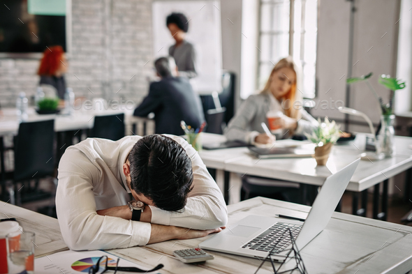 Overworked businessman taking a break from work and napping on his desk ...