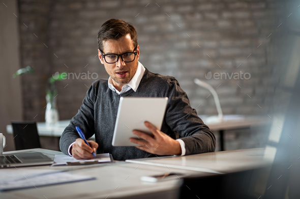 Businessman using touchpad and taking notes on the paper. Stock Photo ...