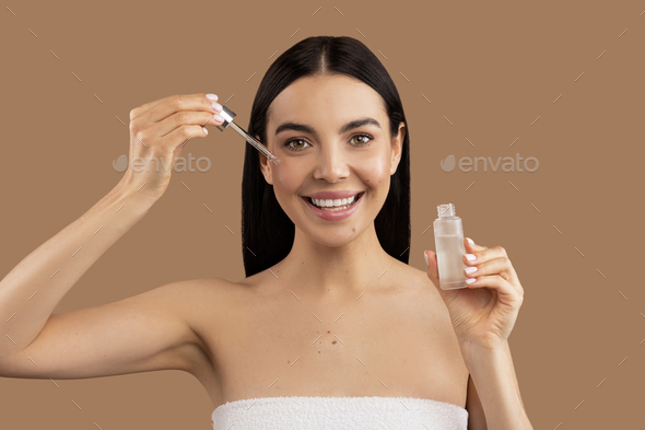 Happy pretty lady using nourishing face serum after shower Stock Photo ...