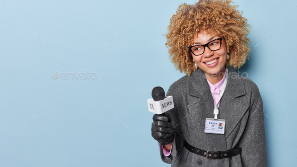 Half length shot of happy successful female TV presenter holds ...