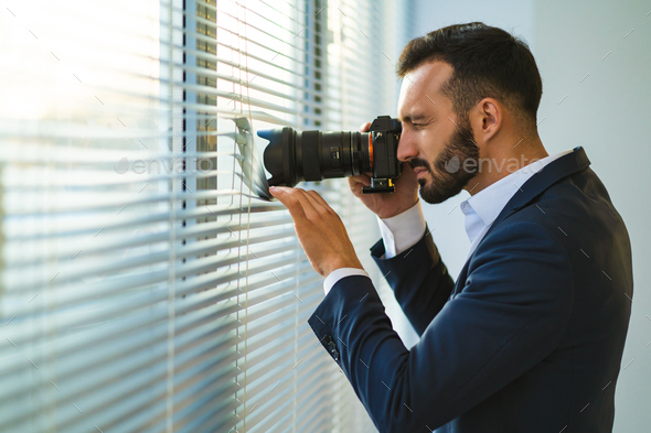 The man with a camera photographing through the blinds Stock Photo by ...
