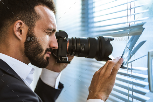 The man with a camera photographing through the blinds Stock Photo by ...