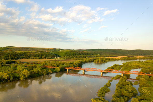 Aerial view of a narrow road bridge stretching over muddy wide river in ...