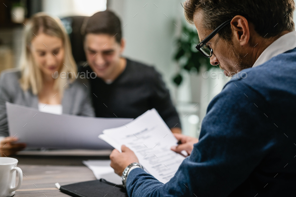 Real estate agent going through paperwork while having a meeting with a ...