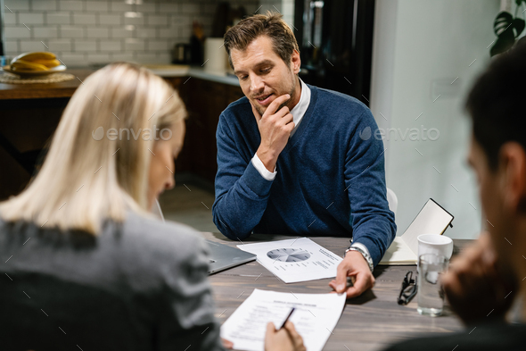 Insurance agent and couple signing a contract during the meeting. Stock ...