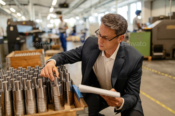Quality control inspector examining manufactured steel cylinders in ...