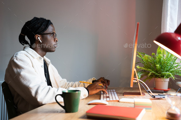 Focused African man freelance web developer writing code, using ...