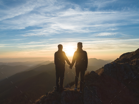 The couple standing on the mountain on the beautiful sunset background Stock Photo by artemp3