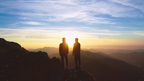 The couple standing on the mountain on the beautiful sunrise background Stock Photo by artemp3