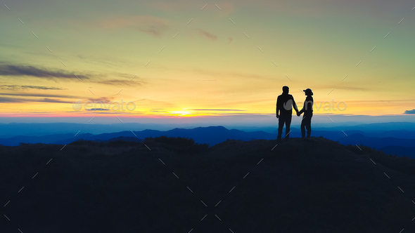 The couple standing on the mountain on the sunrise background Stock Photo by artemp3