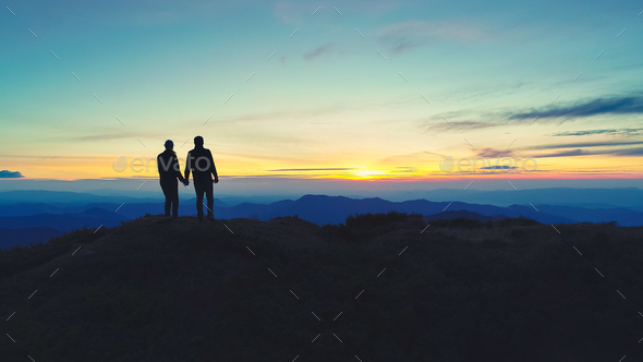 The couple standing on the mountain on the sunset background Stock Photo by artemp3