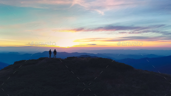 The man and woman standing on the mountain on the sunset background Stock Photo by artemp3