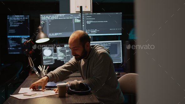 Young programmer typing server code on multiple monitors Stock Photo by DC_Studio