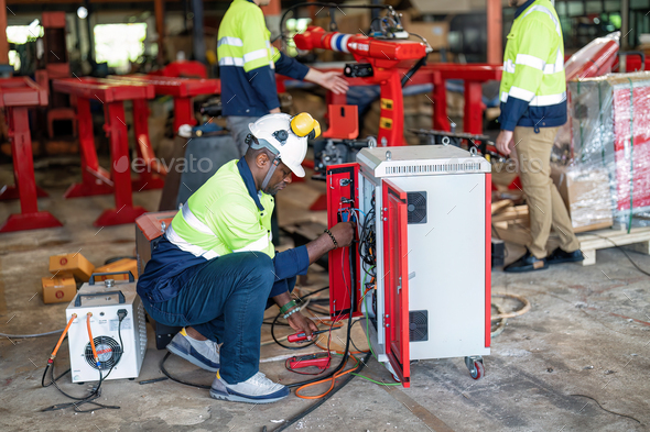 Electrician at robot factory measurement with multimeter testing ...