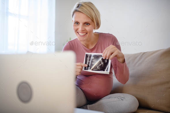 Pregnant woman showing ultrasound photo of her baby to webcam. Stock ...