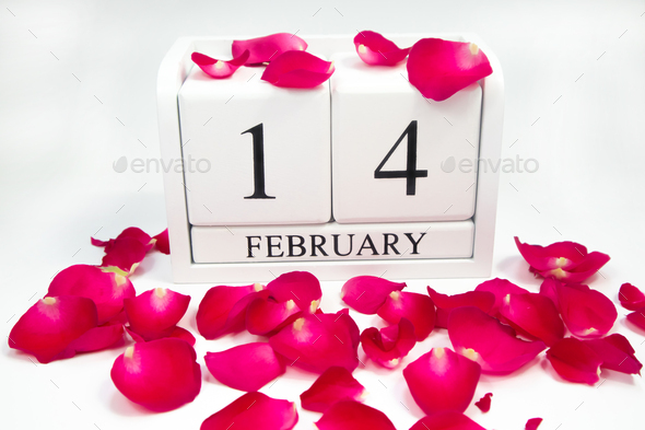 Wooden white calendar February 14 on a white background and rose petals ...