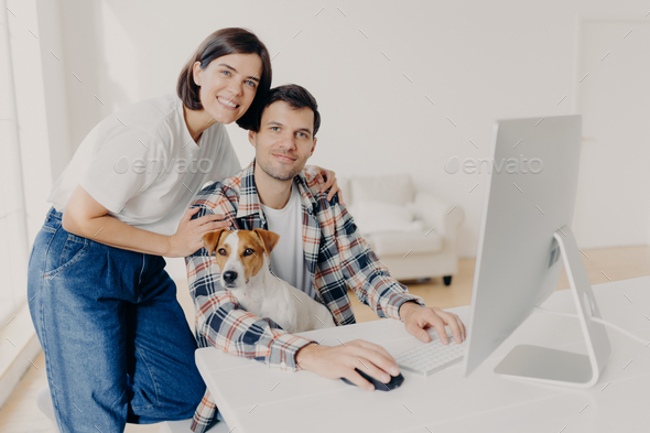 Happy husband and wife pose near computer, keyboard and surf ...