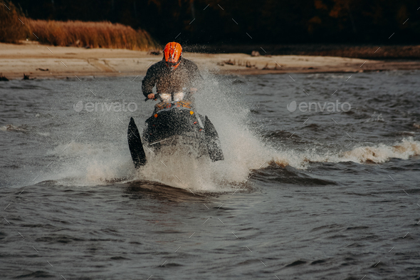 sportsman on a snowmobile rides on the water Stock Photo by loskyt7