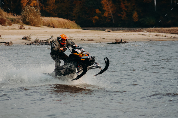 sportsman on a snowmobile rides on the water Stock Photo by loskyt7