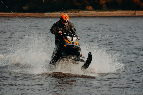 sportsman on a snowmobile rides on the water Stock Photo by loskyt7