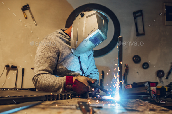 Man worker welding metal with welding machine in a factory or workshop ...