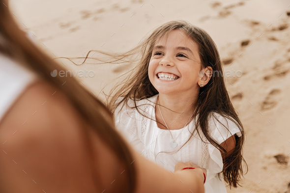 Delighted cute child smiling while having fun with anonymous mom on ...