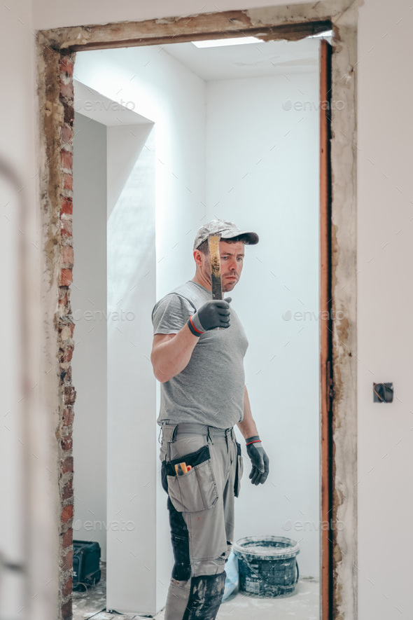 A man working with a crowbar in a doorway. Stock Photo by NataKor5