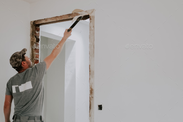 A man working with a crowbar in a doorway. Stock Photo by NataKor5