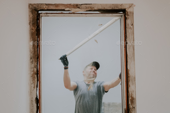 A man working with a crowbar in a doorway. Stock Photo by NataKor5