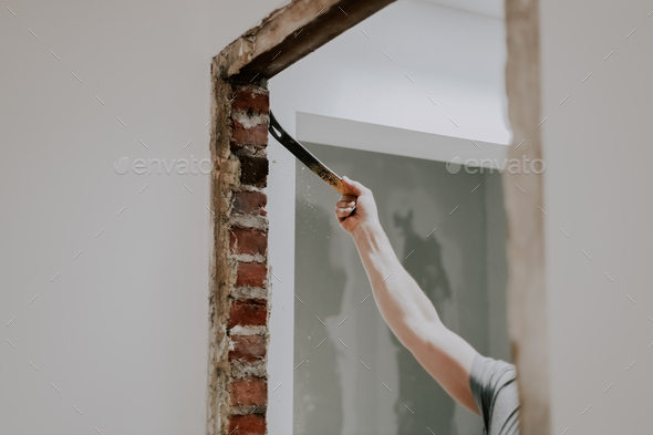 A man working with a crowbar in a doorway. Stock Photo by NataKor5