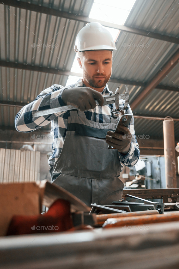 Measuring the object. Factory male worker in uniform is indoors Stock ...