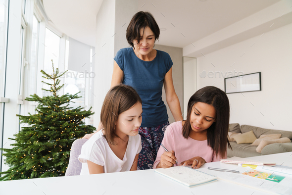 Multiracial sisters doing homework while spending time with their ...