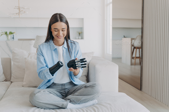 Happy disabled young woman is disassembling bionic arm prosthesis ...