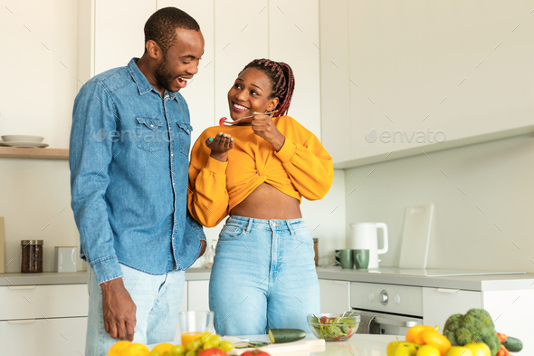Happy young black husband and wife cooking lunch together in kitchen ...