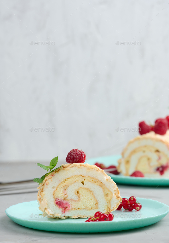 Baked meringue roll with red berries on a round plate, white background ...
